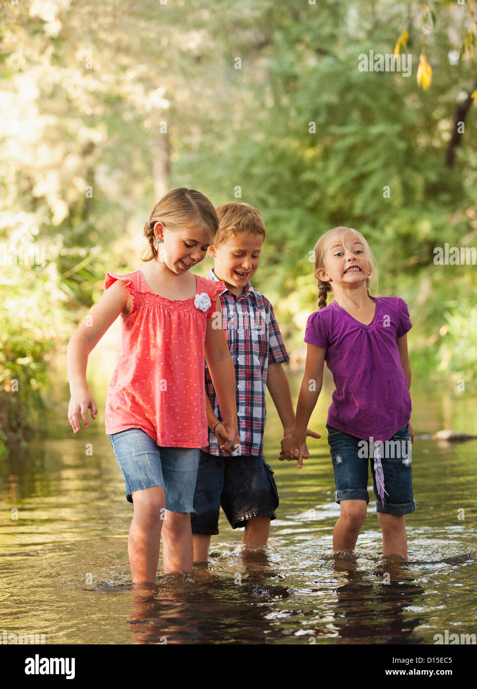 USA, Utah, Lehi, Three kids (4-5, 6-7) holding hands and walking ...