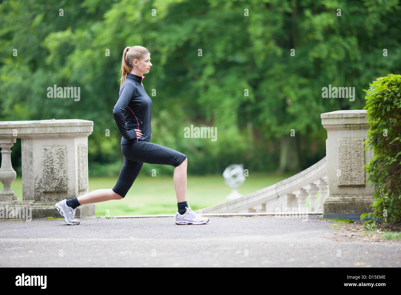 Young woman stretching before jogging Stock Photo - Alamy