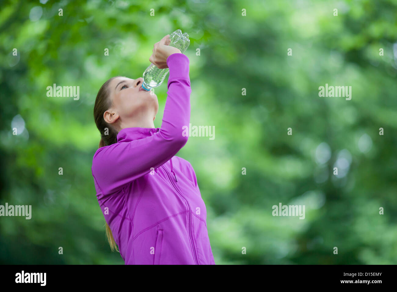Young woman taking break from jogging, drinking water Stock Photo - Alamy