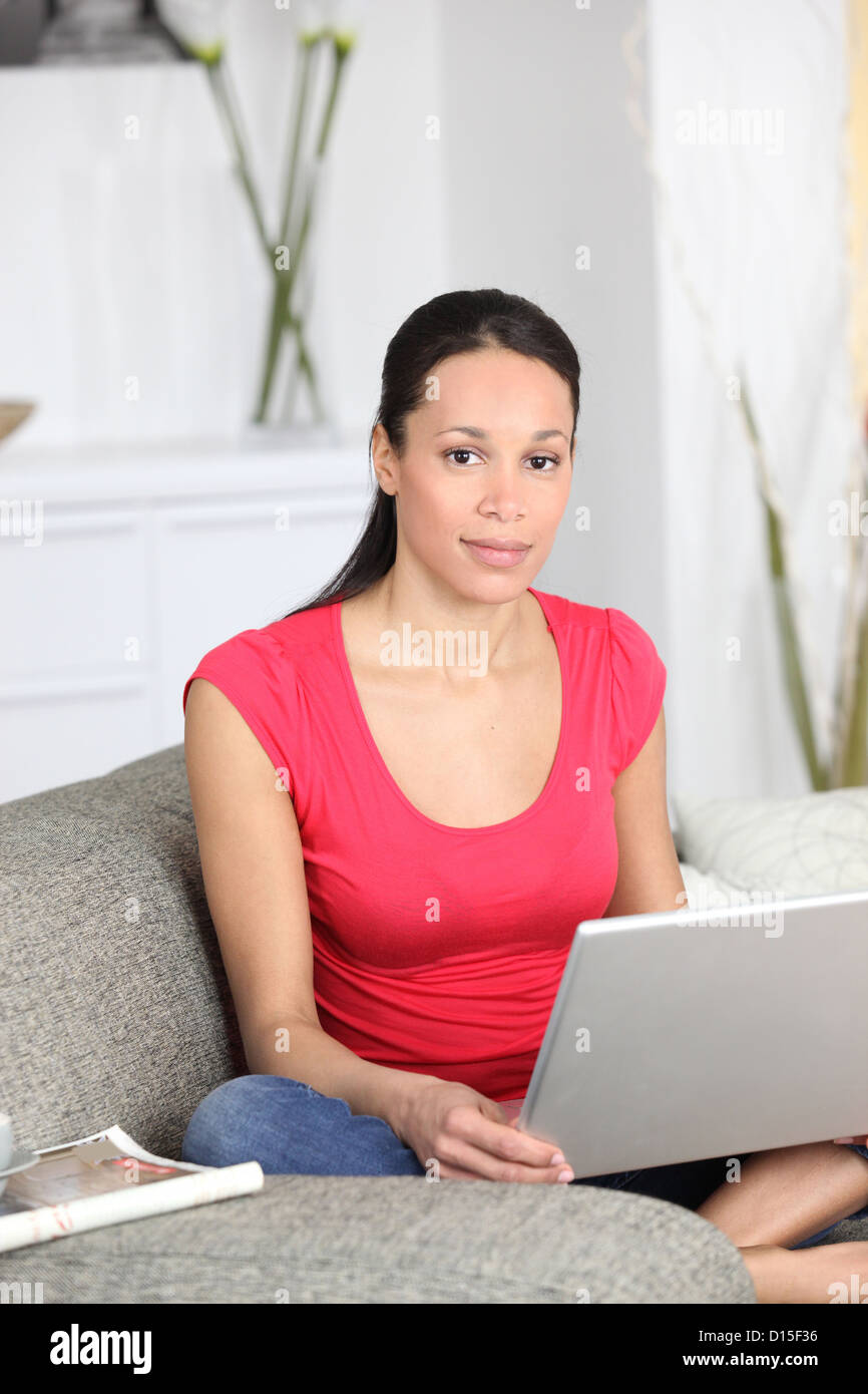 Woman with computer sitting on sofa Stock Photo - Alamy