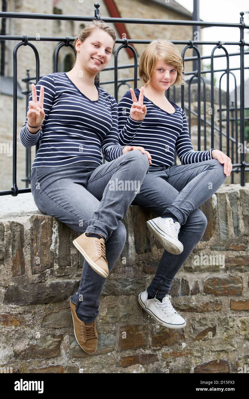 Two teenage girls wearing the same dress and showing peace sign Stock ...