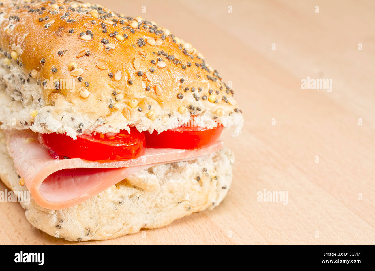 Ham and tomato seeded roll on wooden chopping block Stock Photo - Alamy