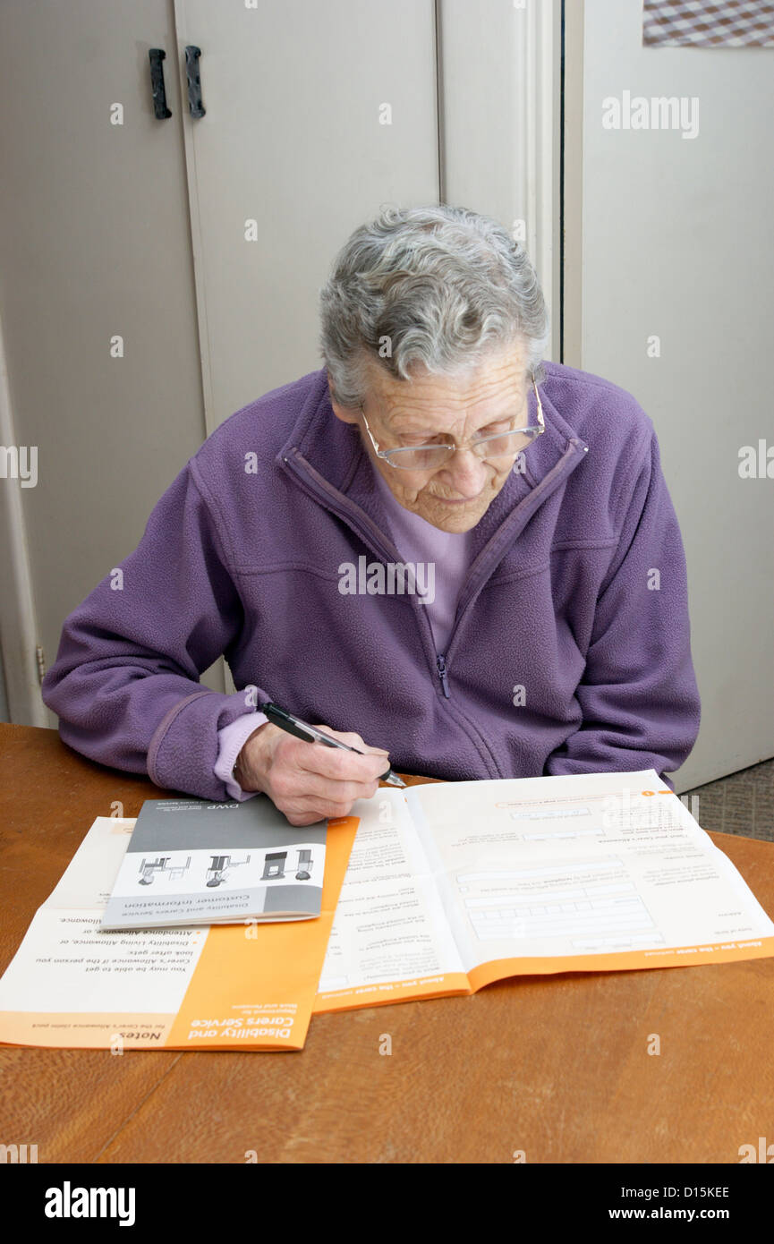 Elderly woman filling in an application form to claim for benefits ...