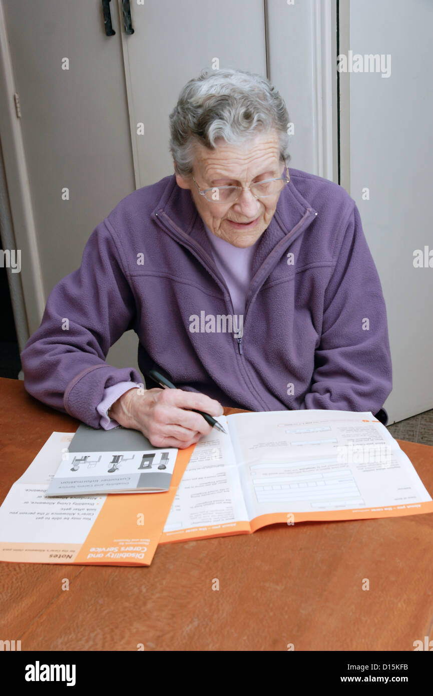 Elderly woman filling in an application form to claim for benefits ...