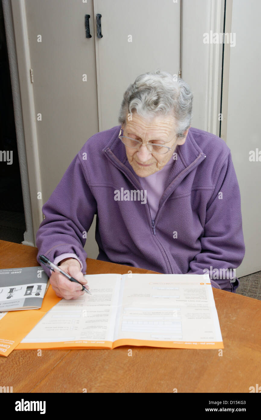 Elderly woman filling in an application form to claim for benefits ...