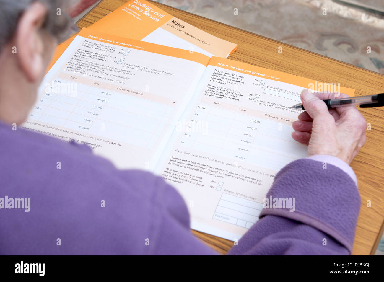 Elderly woman filling in an application form to claim for benefits ...