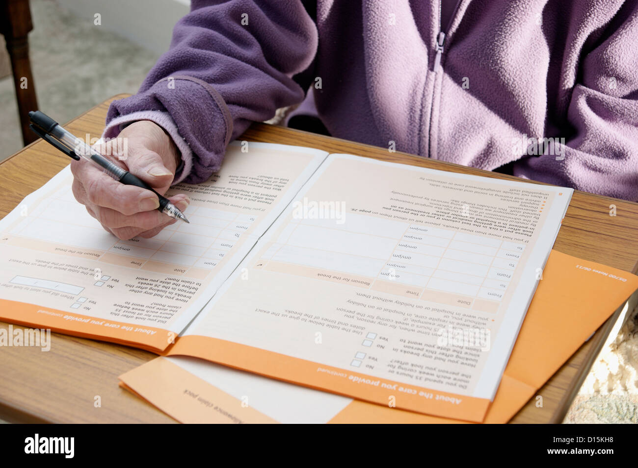 Elderly woman filling in an application form to claim for benefits ...