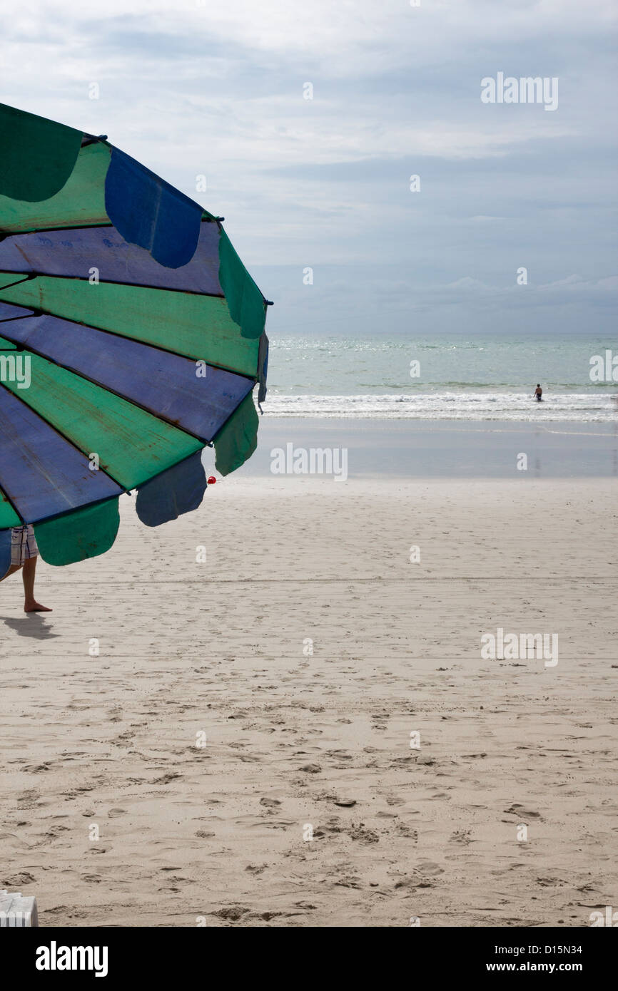 Tourist walks by open beach umbrella Stock Photo - Alamy