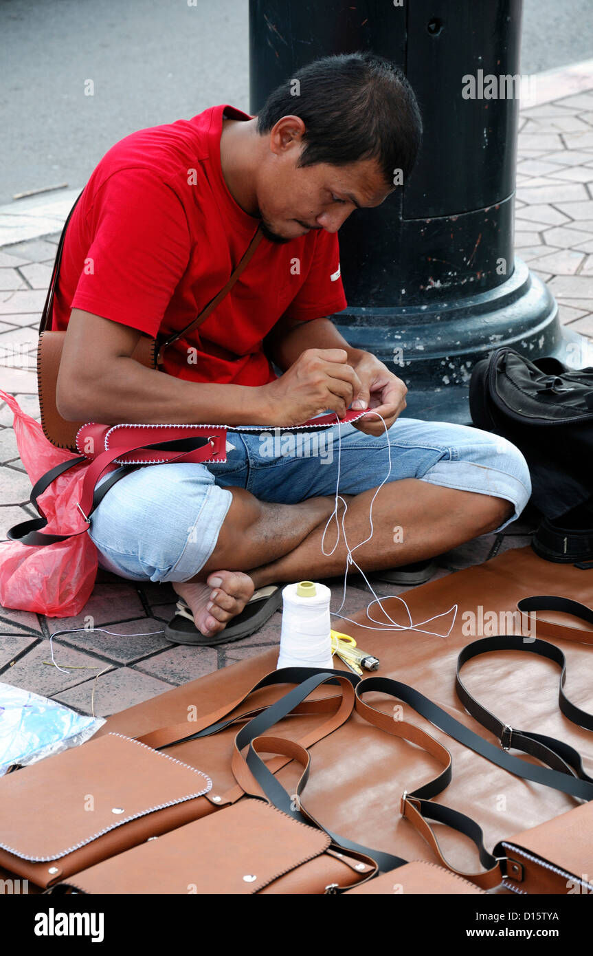 man stitching stitch leather handbags bags purses street seller market ...