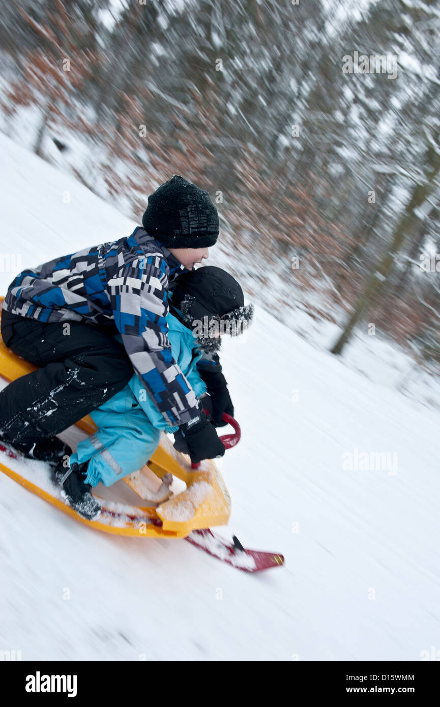 Two young boys going downhills on a modern snow sledge Stock Photo - Alamy