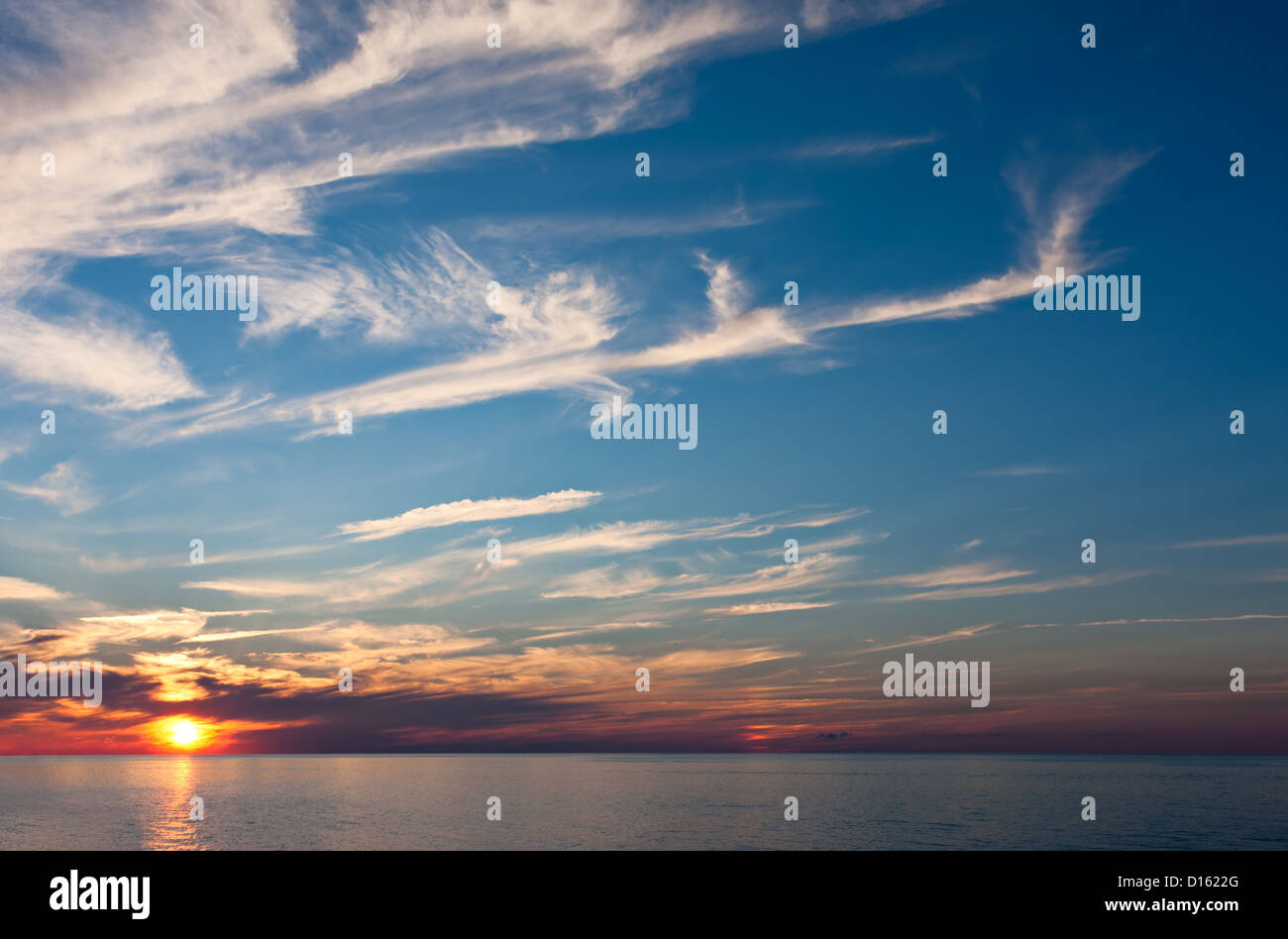 An Evening Sunset Over Water. The sky is blue at the top with multi ...