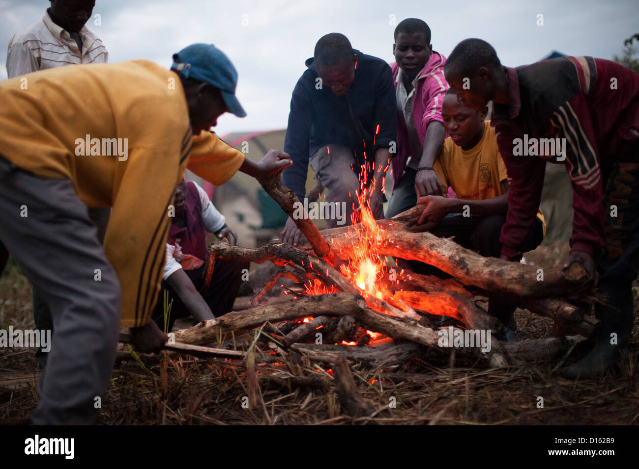 Men build a campfire in Kitugutu Village, Kyenjojo District, Uganda ...