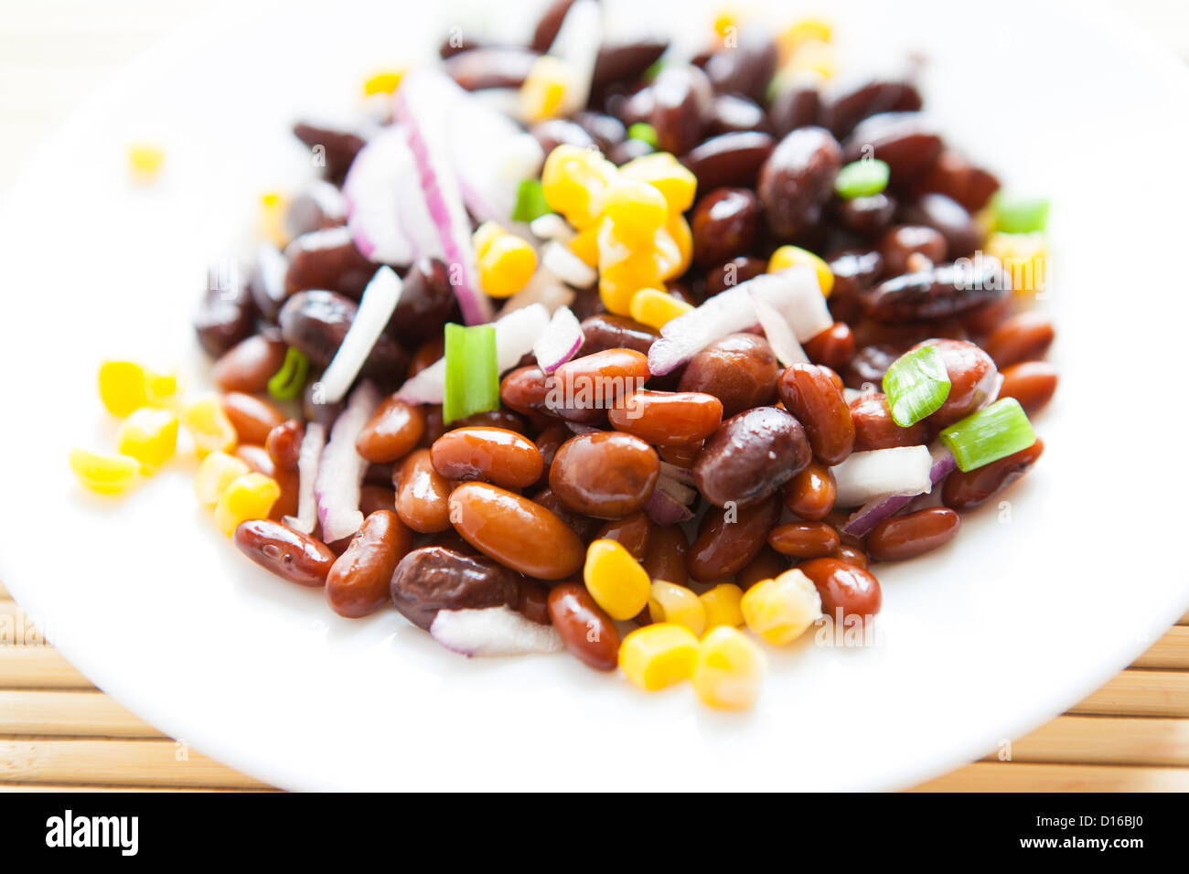 Cooked beans and maize and onions on a white plate, close up Stock ...
