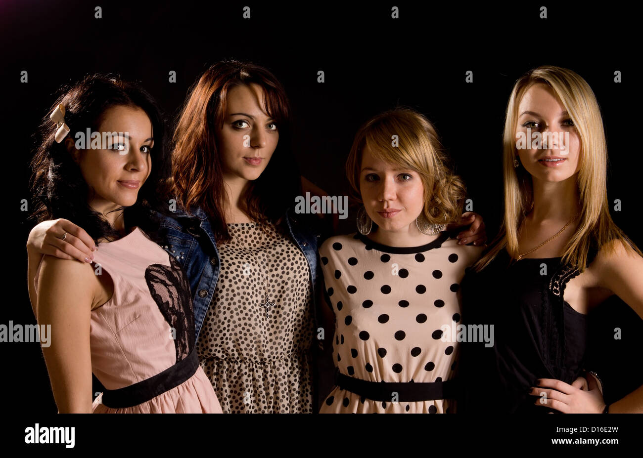 Four stylish young teenage girls on a night out pose in a line in their ...