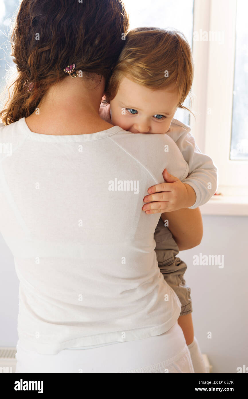 Mother holding her baby near window. Rear view Stock Photo - Alamy