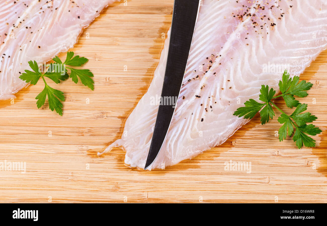 tip of fillet knife on top of white skinless fish with spices and ...