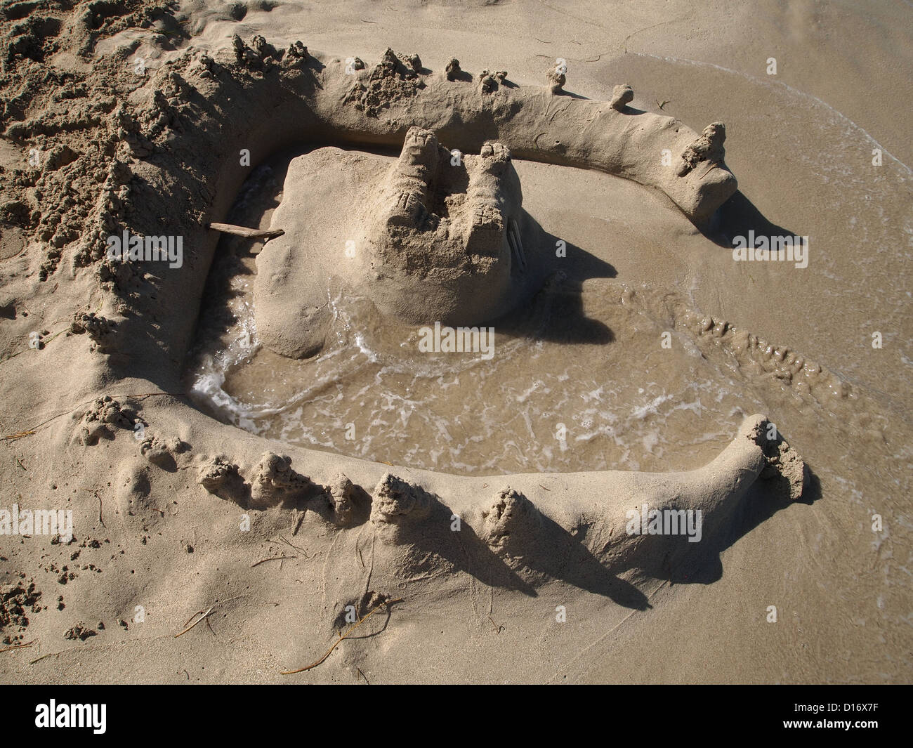A wave damaged a sandcastle Stock Photo - Alamy