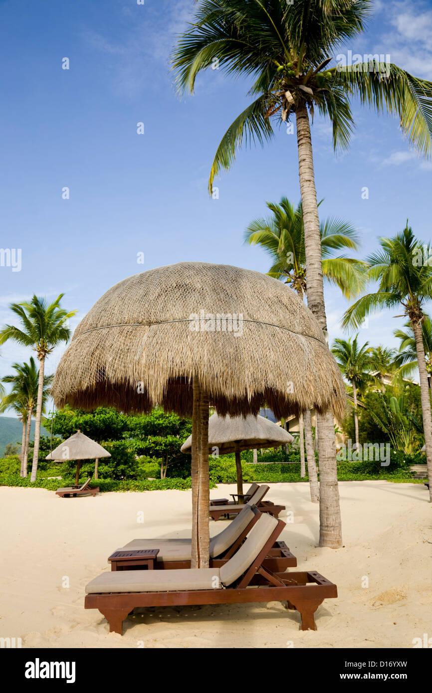 Thatched sunshade and chaise lounge in summer resort Stock Photo - Alamy
