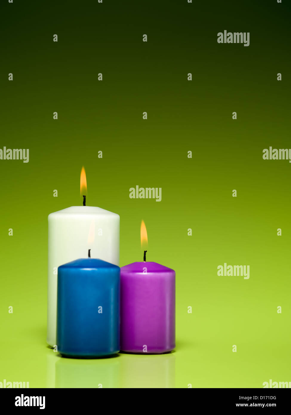 closeup of a group of three burning candles on green gradient ...