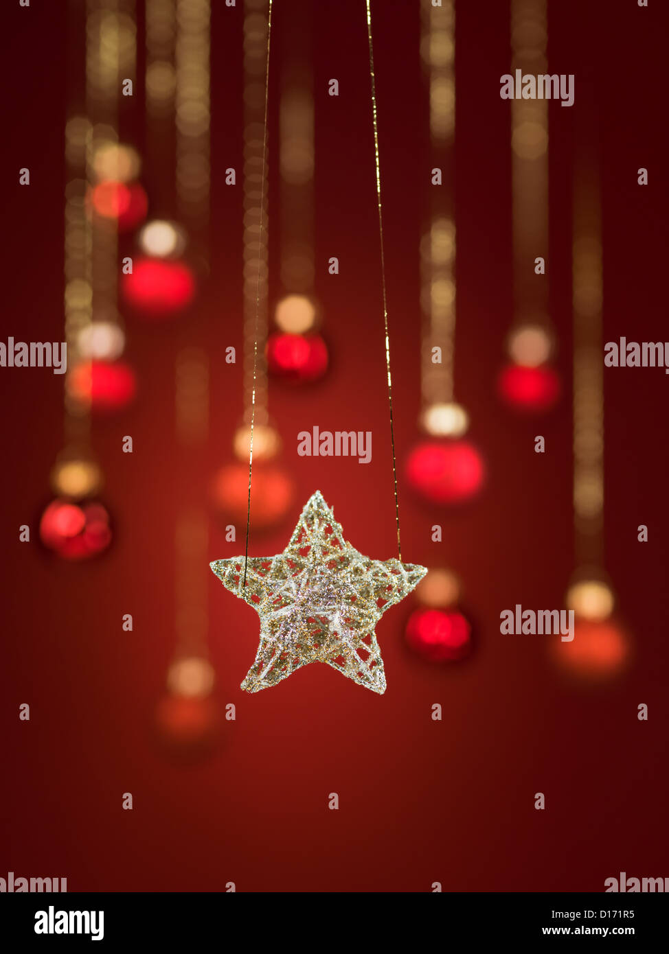 closeup of hanging glittery star with golden threads on red gradient ...