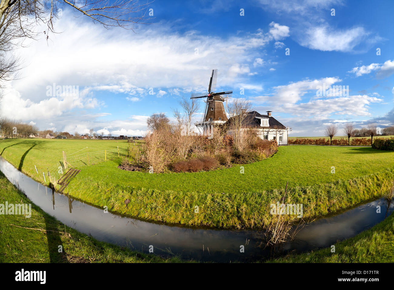 Dutch windmill on green pasture over blue sky and canal Stock Photo - Alamy