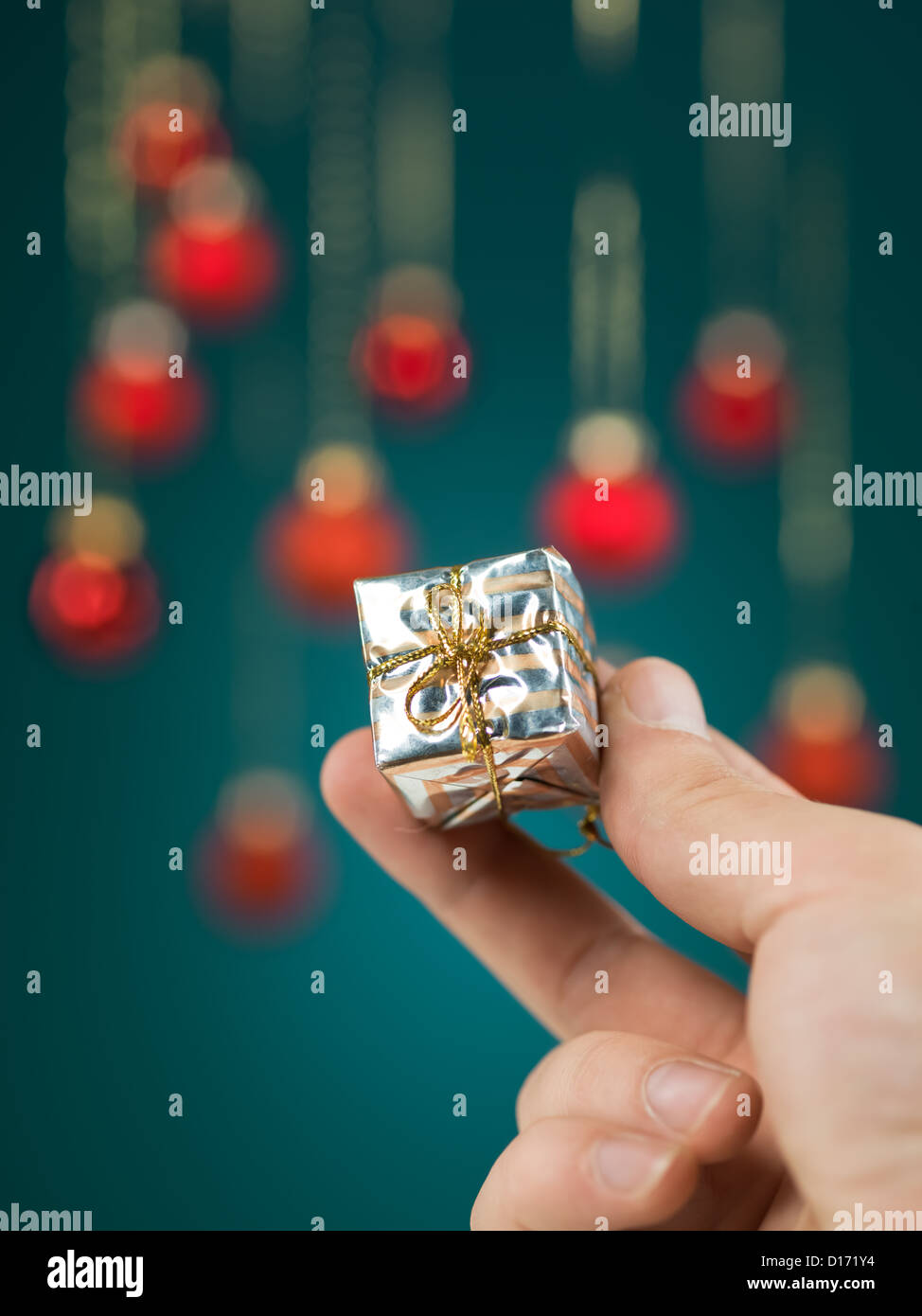 closeup of hanging small present handheld with golden strings on blue ...