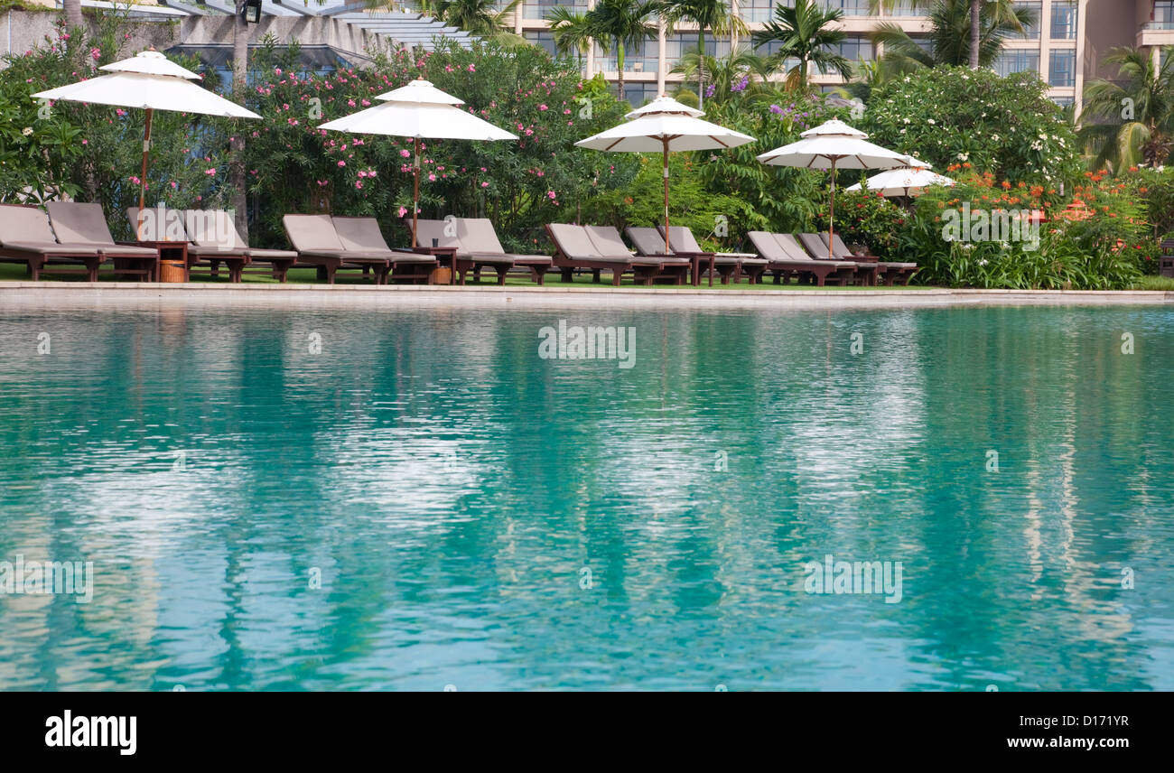Swimming pool in the tourist resort with reclining chairs and sunshade ...