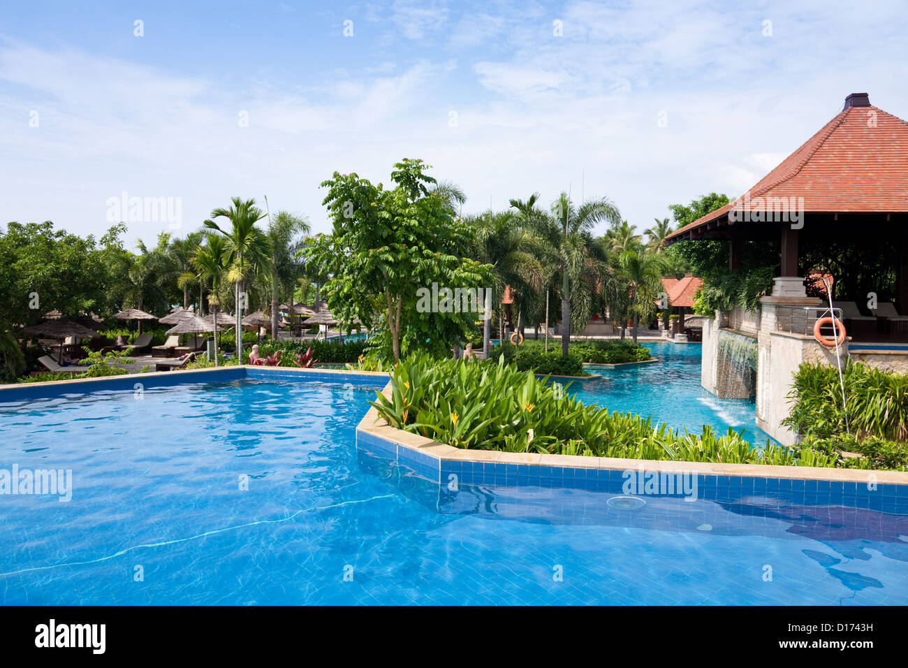 Swimming pool in tropical garden with flowers and trees at the poolside ...