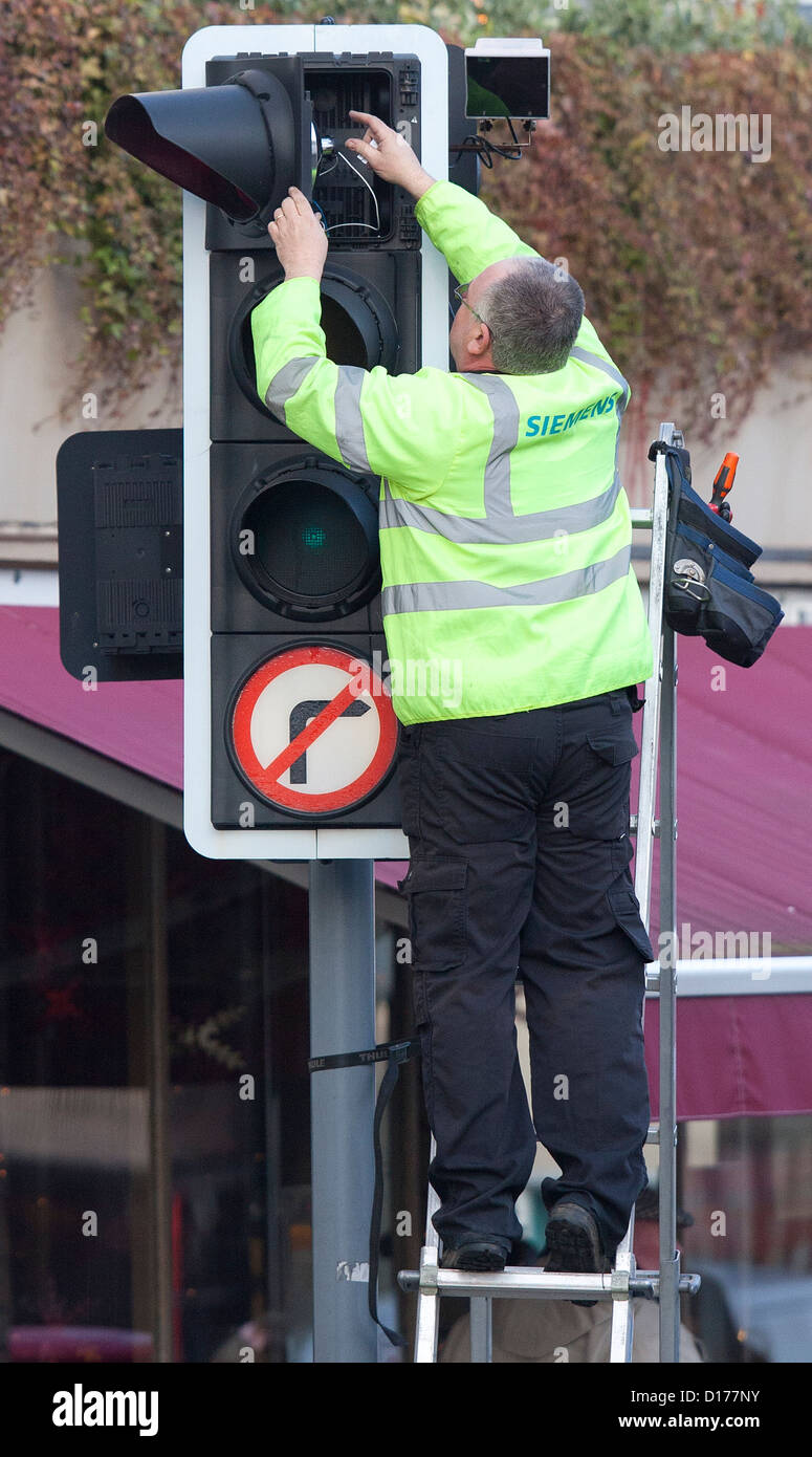 A workman up a ladder maintains a set of Traffic lights Stock Photo - Alamy