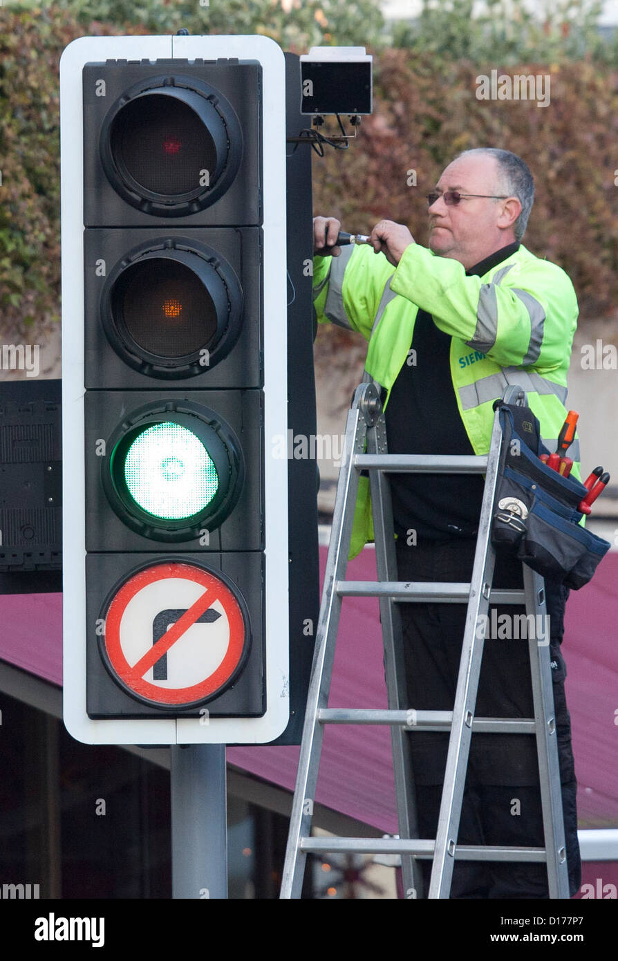 A workman up a ladder maintains a set of Traffic lights Stock Photo - Alamy