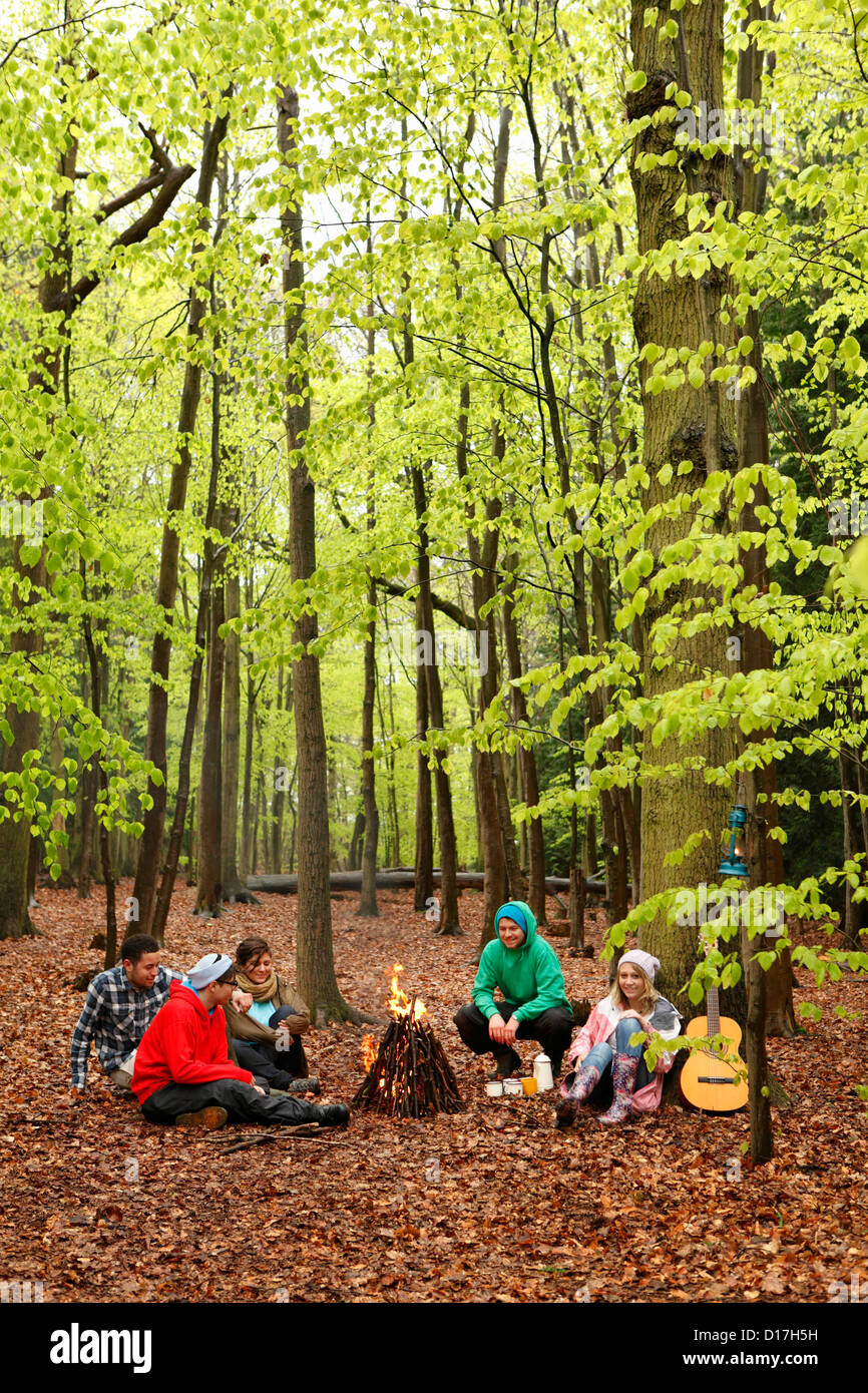 Friends sitting around campfire together Stock Photo - Alamy