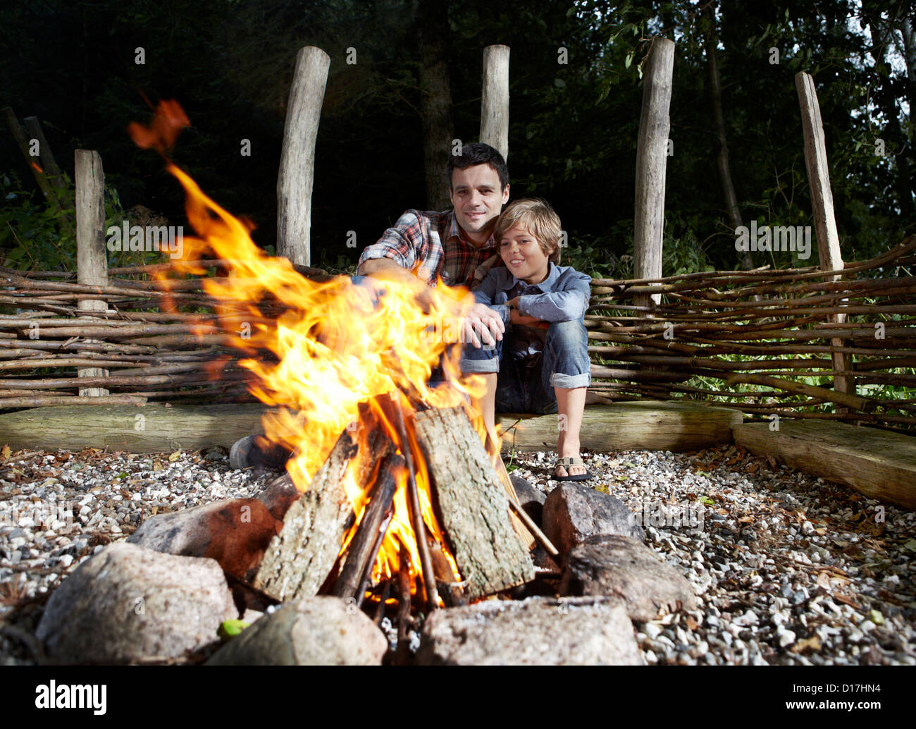 Father and son sitting by fire outdoors Stock Photo - Alamy