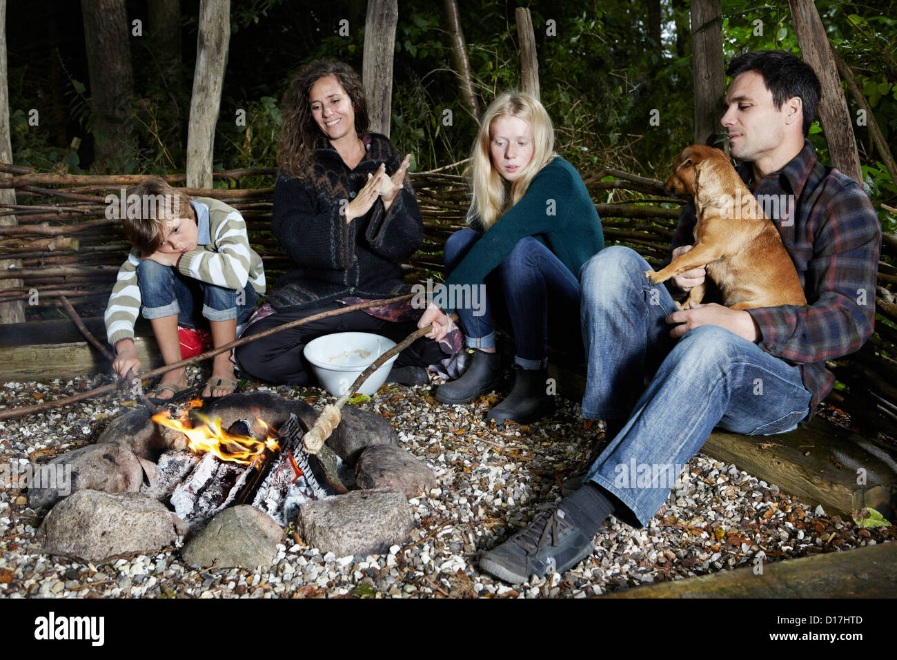 Family relaxing by fire outdoors Stock Photo - Alamy