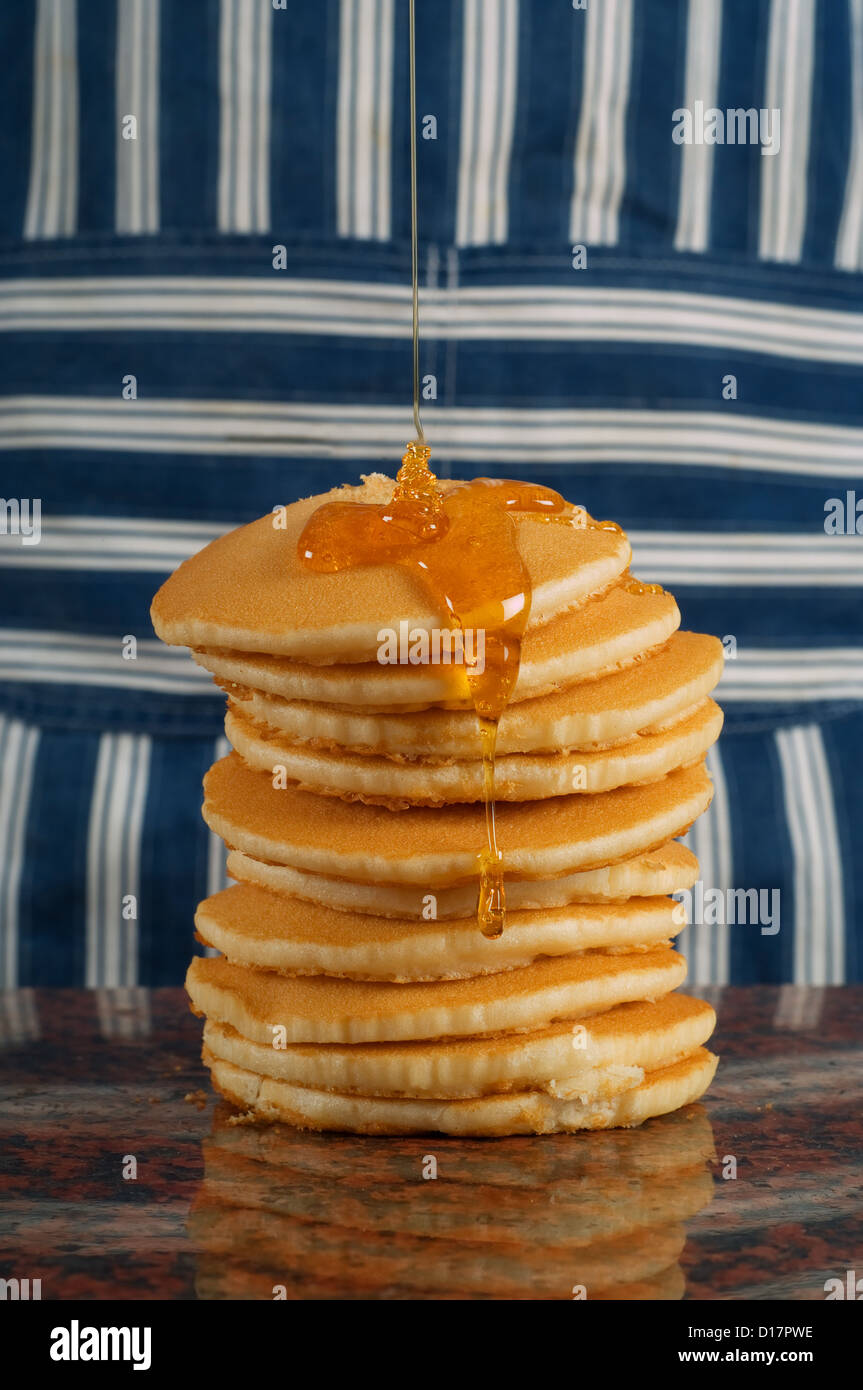 Chef or cook with striped apron pouring syrup on flapjacks or pancakes ...