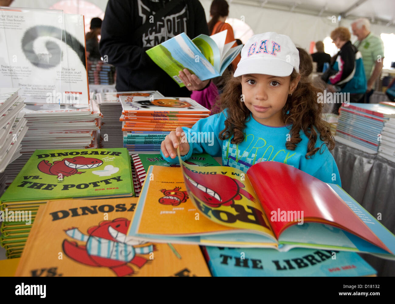 Young girl looks over stack of children's books during the Texas Book ...