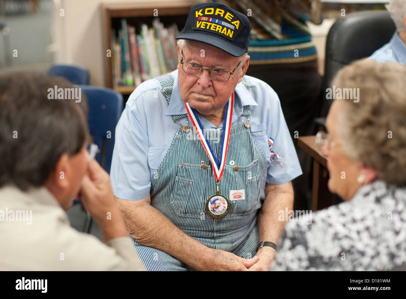 Elderly white male military veteran speaks with several people at ...