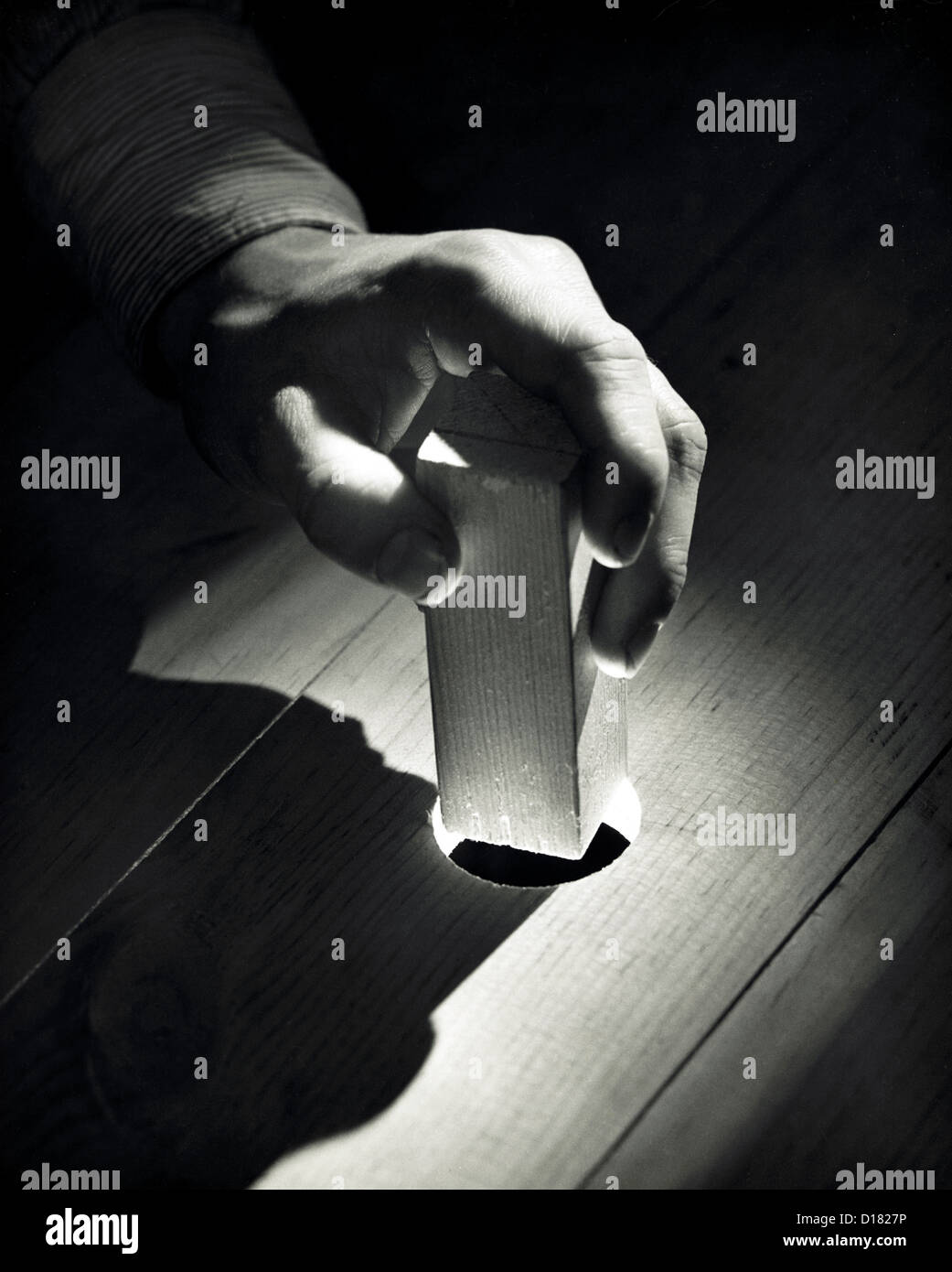 Close-up of man's hand trying to push square block into round hole ...