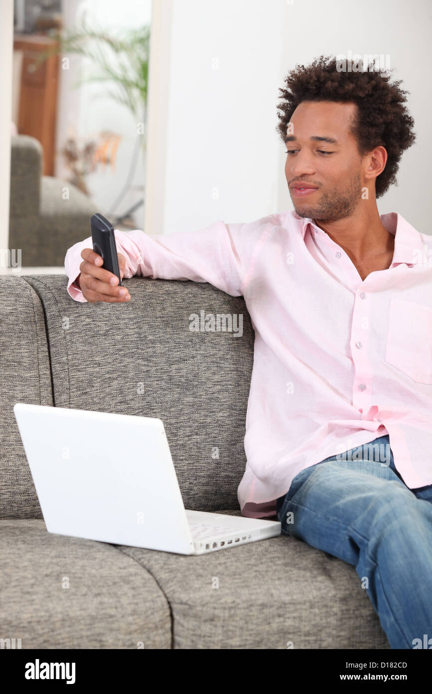 Young man texting whilst sat on sofa Stock Photo - Alamy