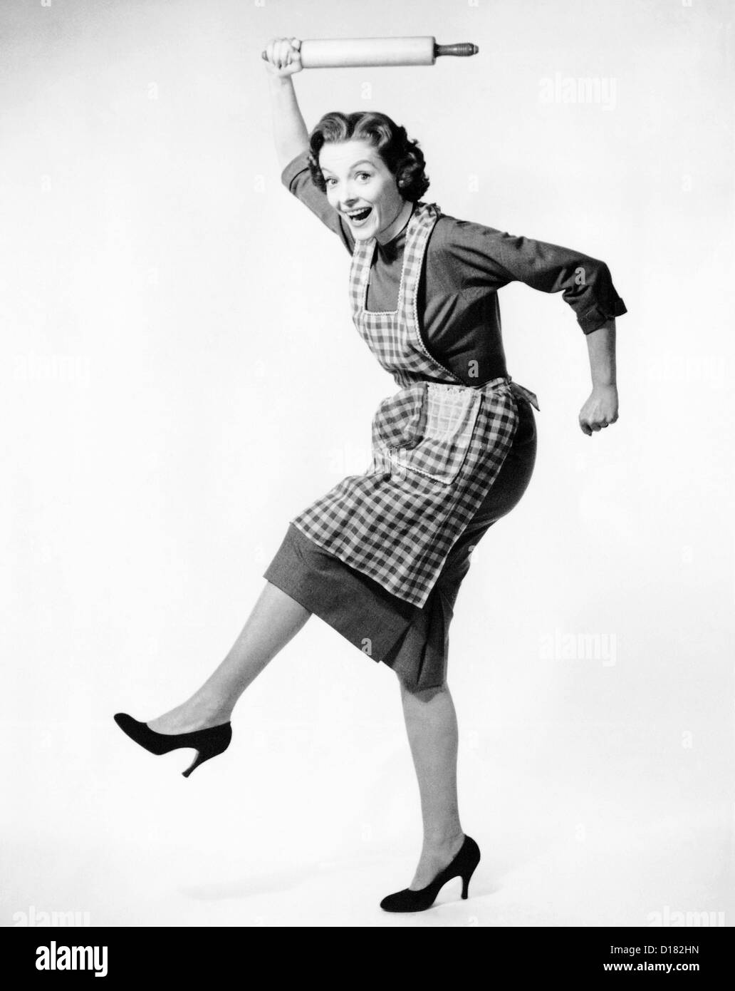 Exuberant woman with raised rolling pin Stock Photo - Alamy