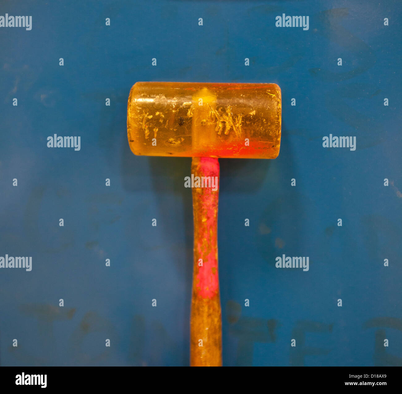 Orange mallet against a blue background Stock Photo - Alamy