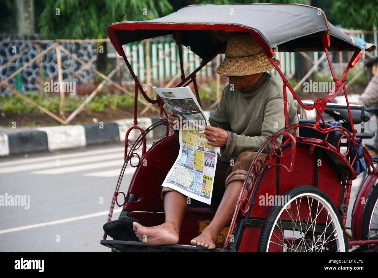 A man on his cycle rickshaw reading newspaper in Banjarmasin, Indonesia ...