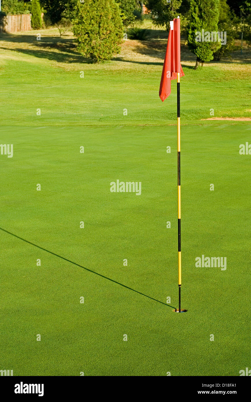 Striped golf flag in green hole with morning shadow on grass Stock ...