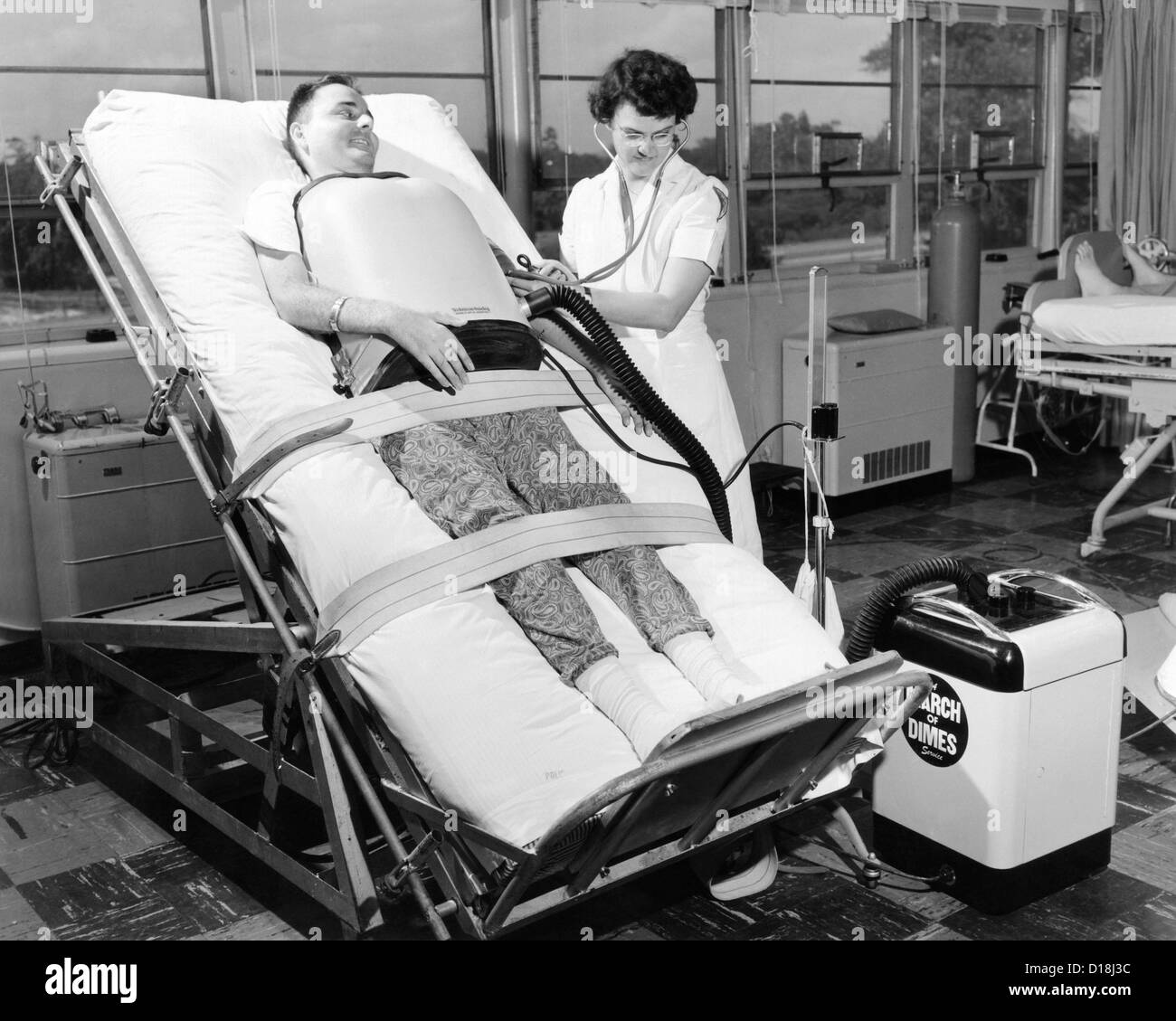 A 30 year old polio patient wearing a chest respirator on a standing ...