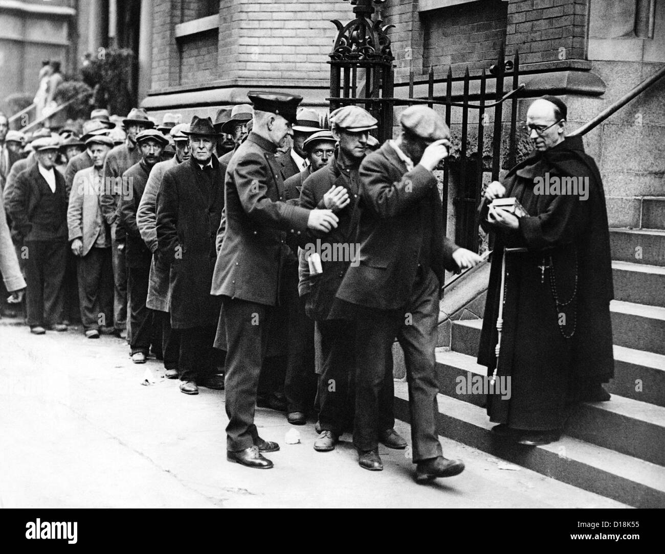 Breadline for the needy, probably in New York City. A Priest hands out ...
