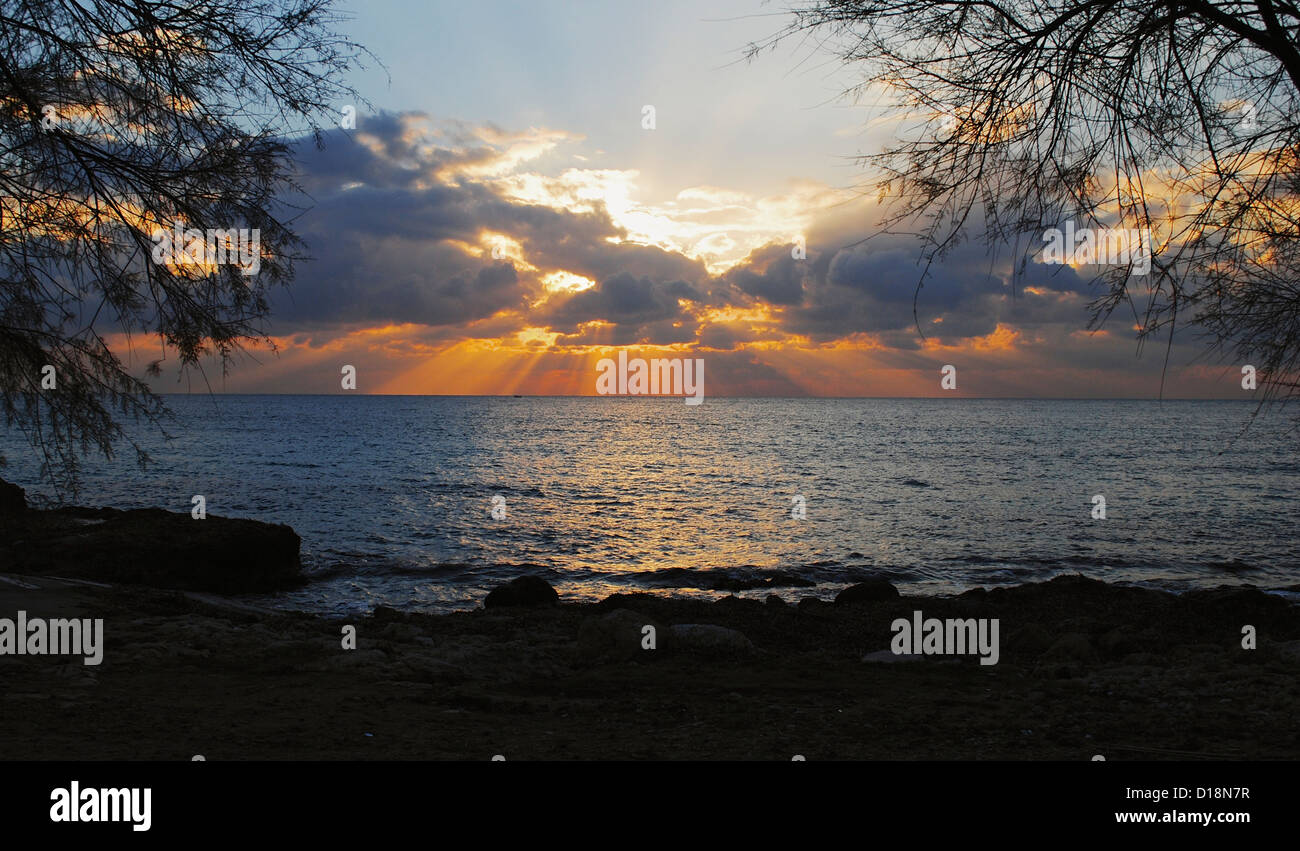 A beatifull sunset with the sun behind the clouds projecting its rays ...