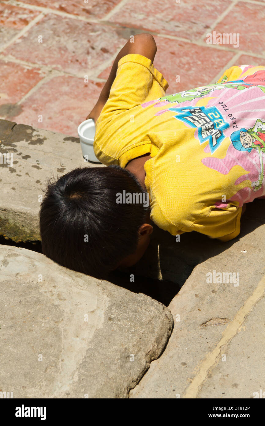 Boy searching in hole in Phnom Penh, Cambodia Stock Photo - Alamy