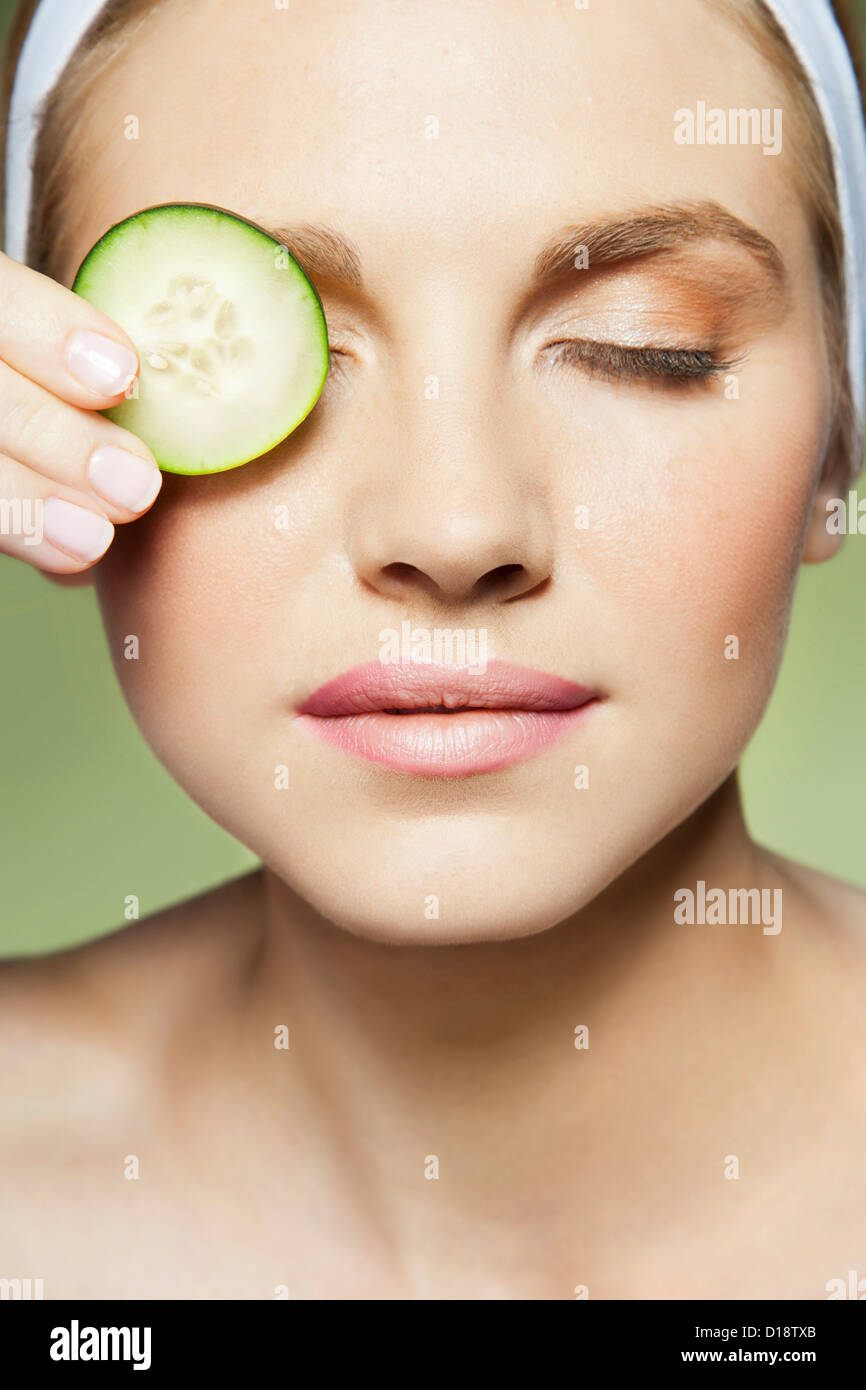 Woman covering eye with piece of cucumber Stock Photo - Alamy
