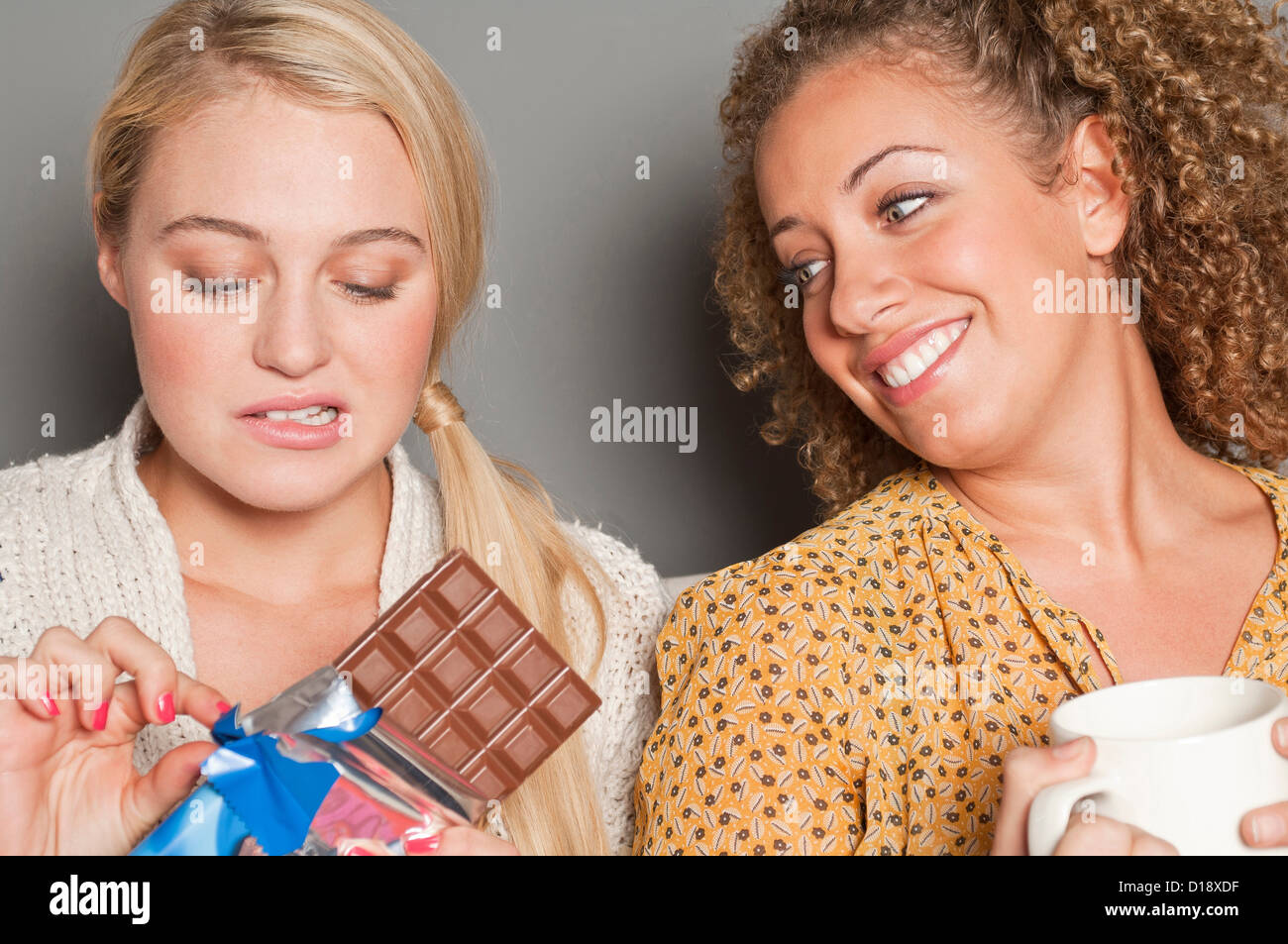 Woman staring at friend holding chocolate Stock Photo - Alamy