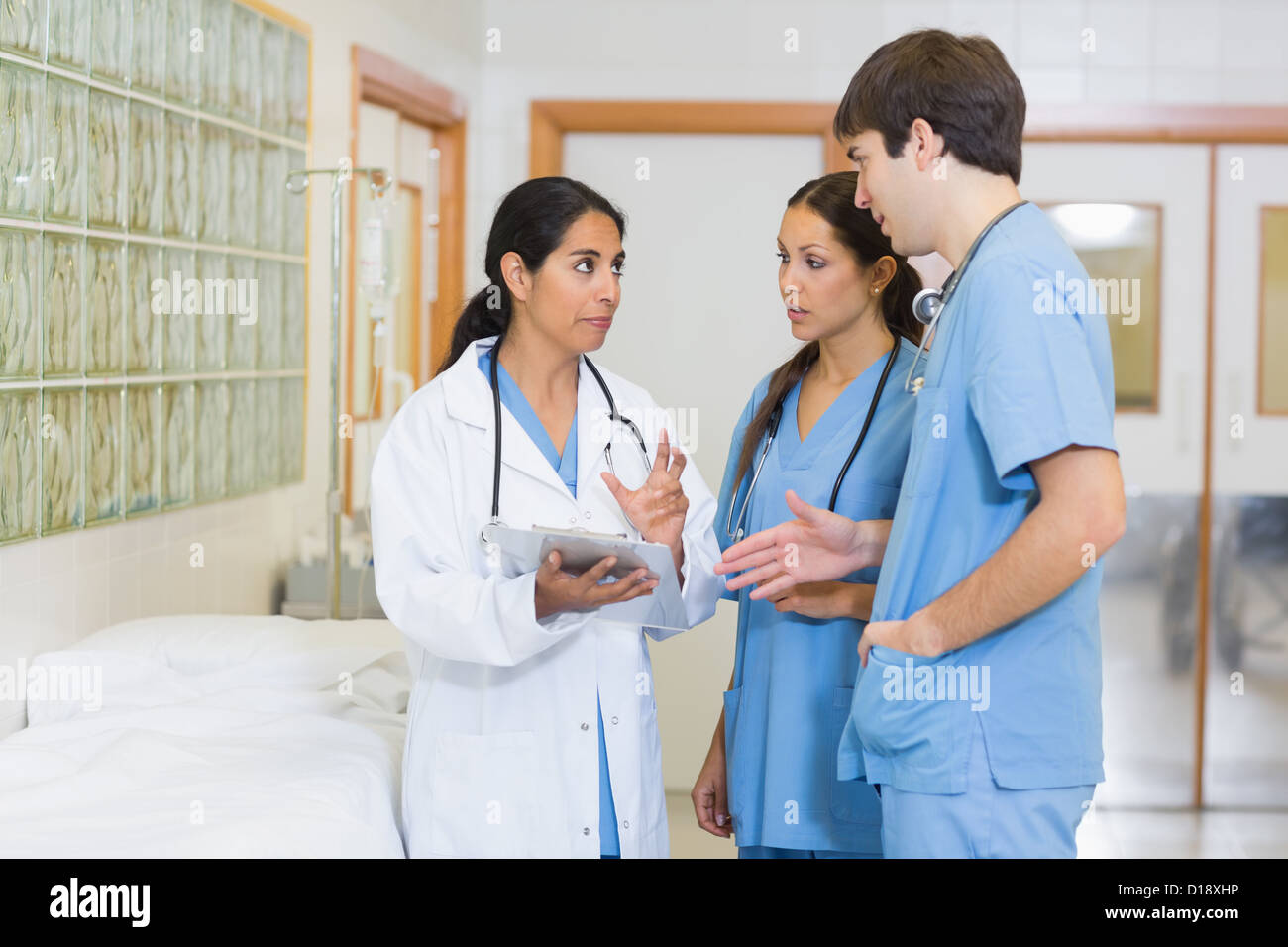 Female doctor talking to a male and a female nurse in a hallway Stock ...