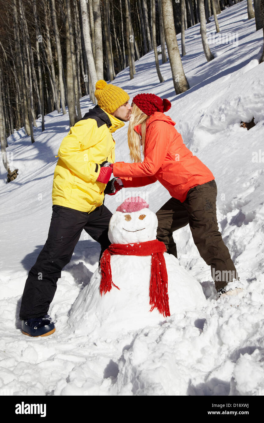 Couple kissing by snowman Stock Photo - Alamy